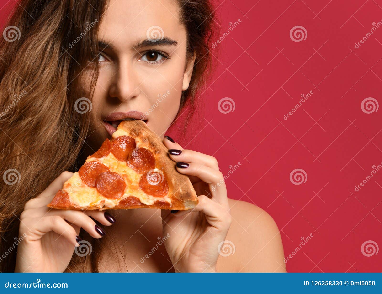 Young Beautiful Woman Eating Slice Of Pepperoni Pizza On Pink Red Stock