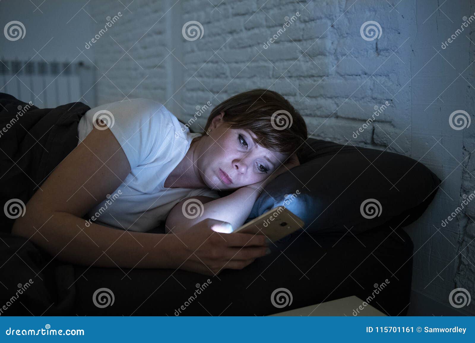 Young Beautiful Woman Lying Bored In Bed Using Smart Phone Late At