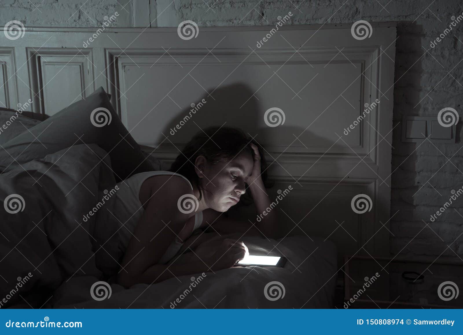 Young Beautiful Woman Lying Bored In Bed Using Smart Phone Late At