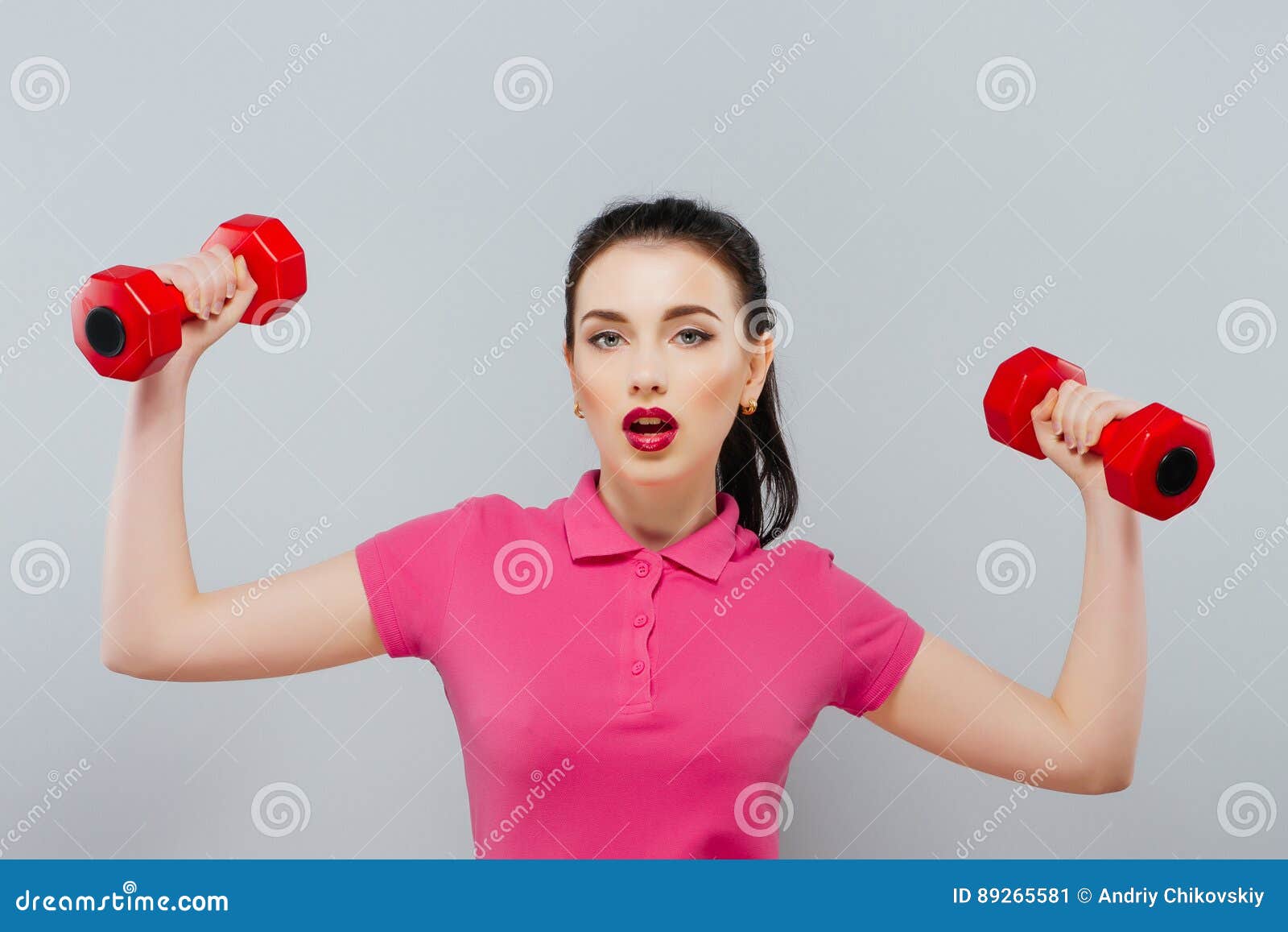 Young Beautiful Woman Playing with Two Dumbbells on Grey Background ...