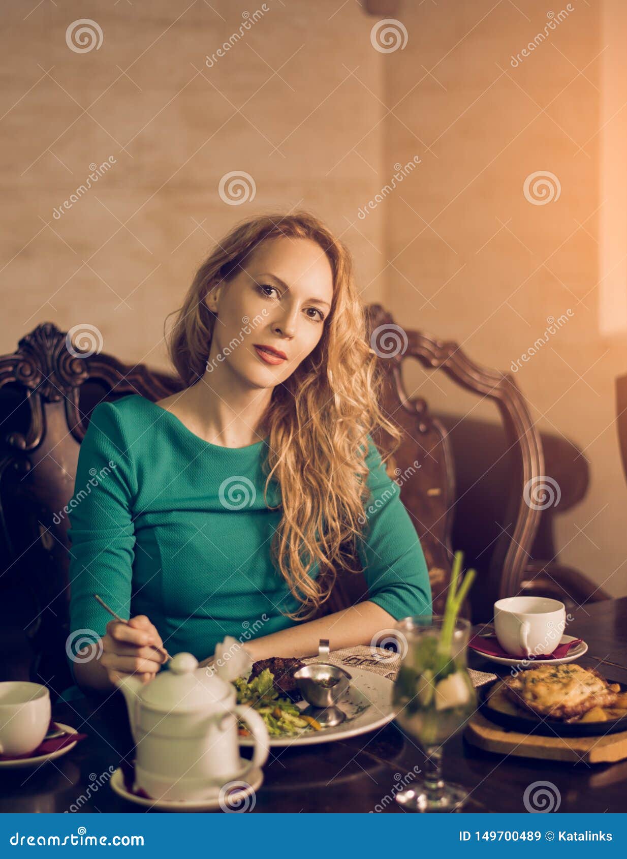 Young Beautiful Woman Is Sitting At The Table And Having Dinner In The