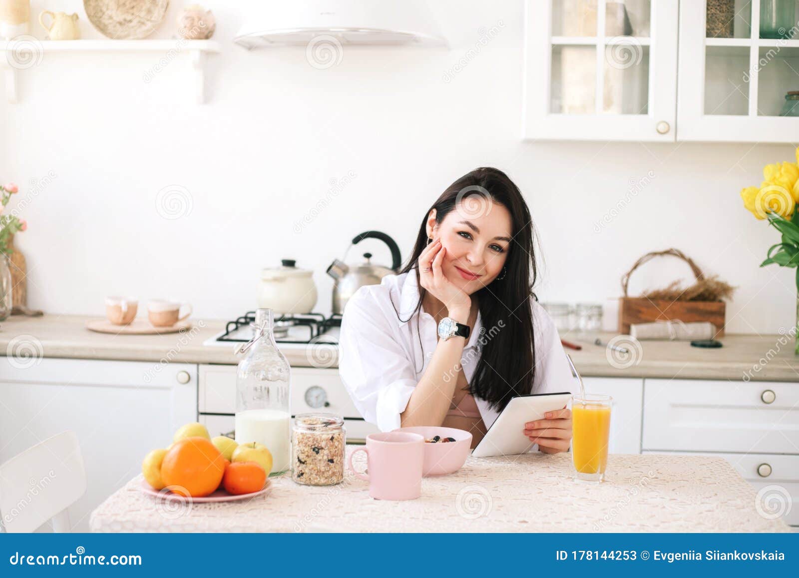 Young Beautiful Woman Using Digital Tablet while Breakfast in Kitchen ...