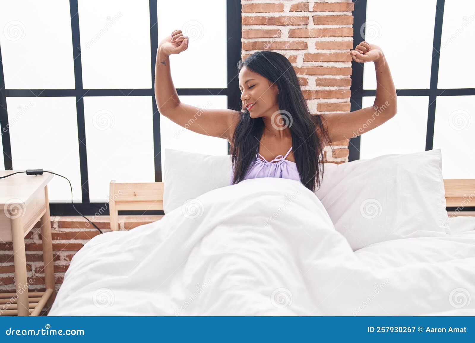 Young Beautiful Woman Waking Up Stretching Arms At Bedroom Stock Image