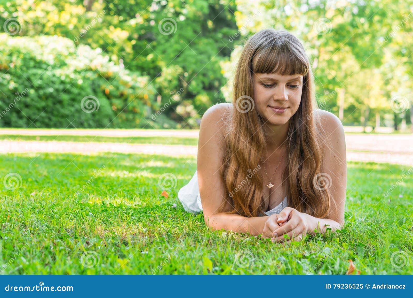 Young Beautiful Woman In White Dress Lying On The Grass Stock Image