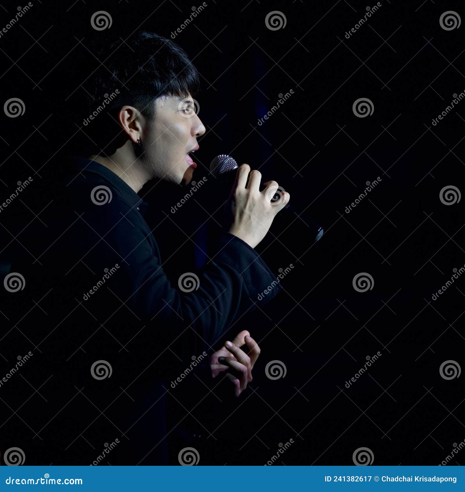 Young Black-haired Asian Singer with a Microphone Singing on Stage. the ...