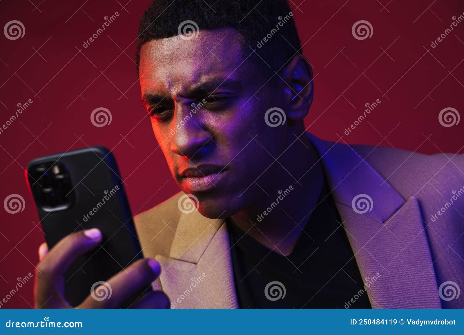 Young Black Man Dressed in Jacket Frowning while Using Cellphone Stock ...