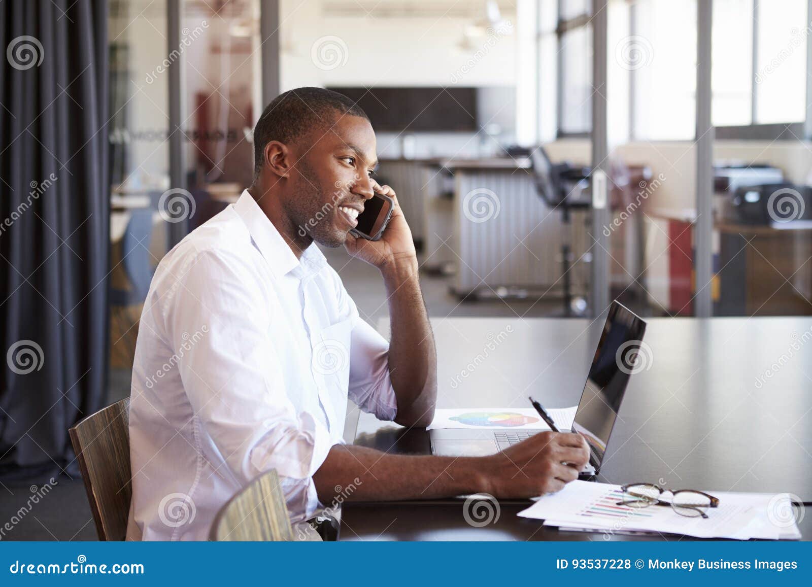 Young Black Man with Laptop on the Phone in an Office Stock Photo ...