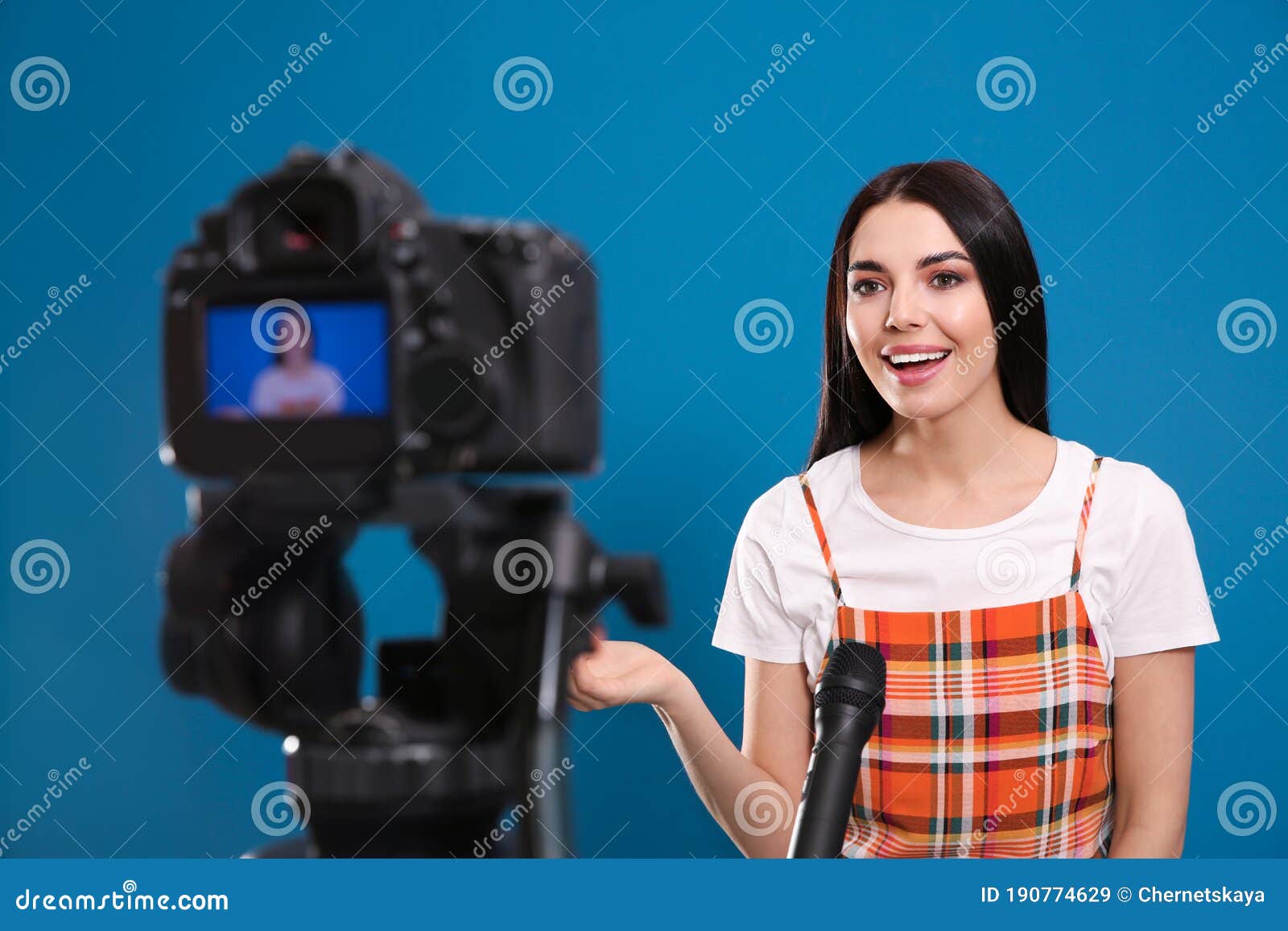 Young Blogger with Microphone Recording Video on Camera Against ...