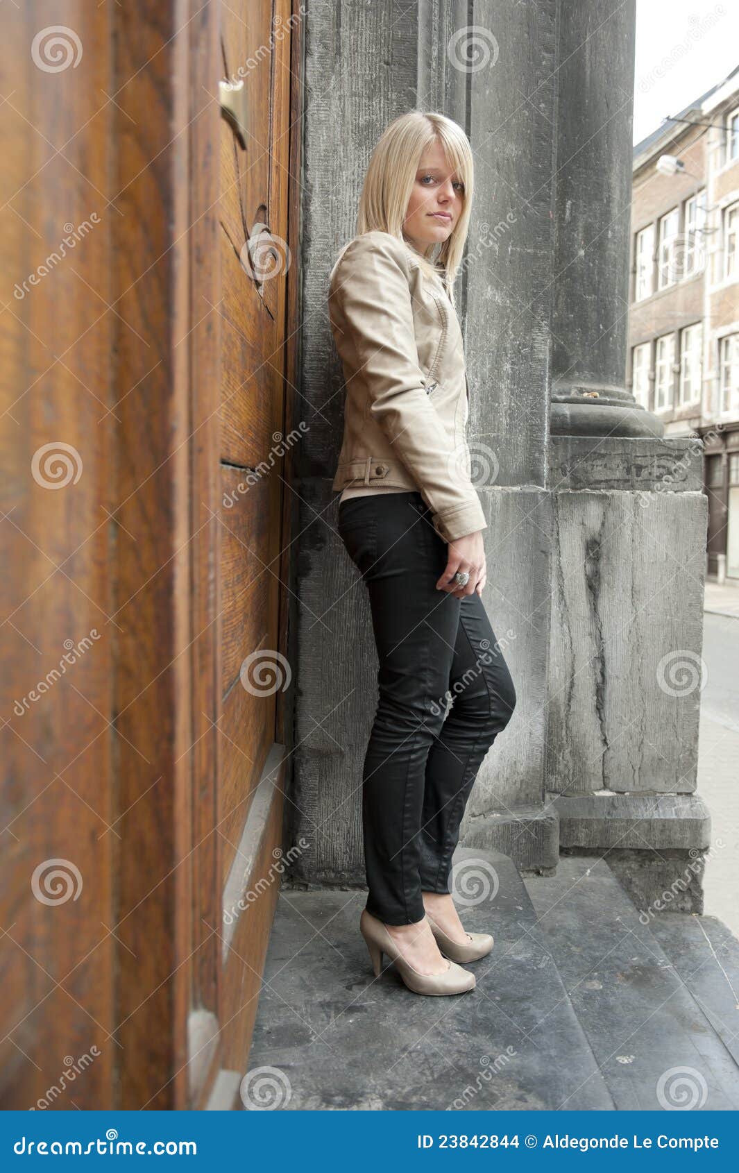 Young Blond Woman Standing Against a Door Stock Photo - Image of urban ...