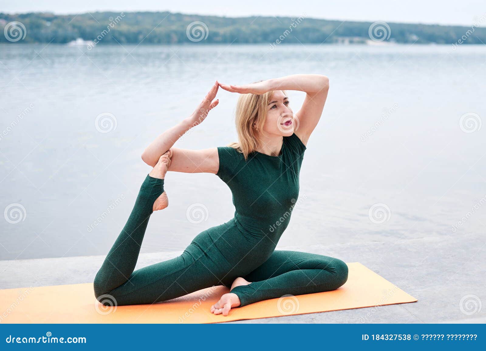 Young Blond Woman Wearing Green Overall With Bare Feet Doing Yoga Pose