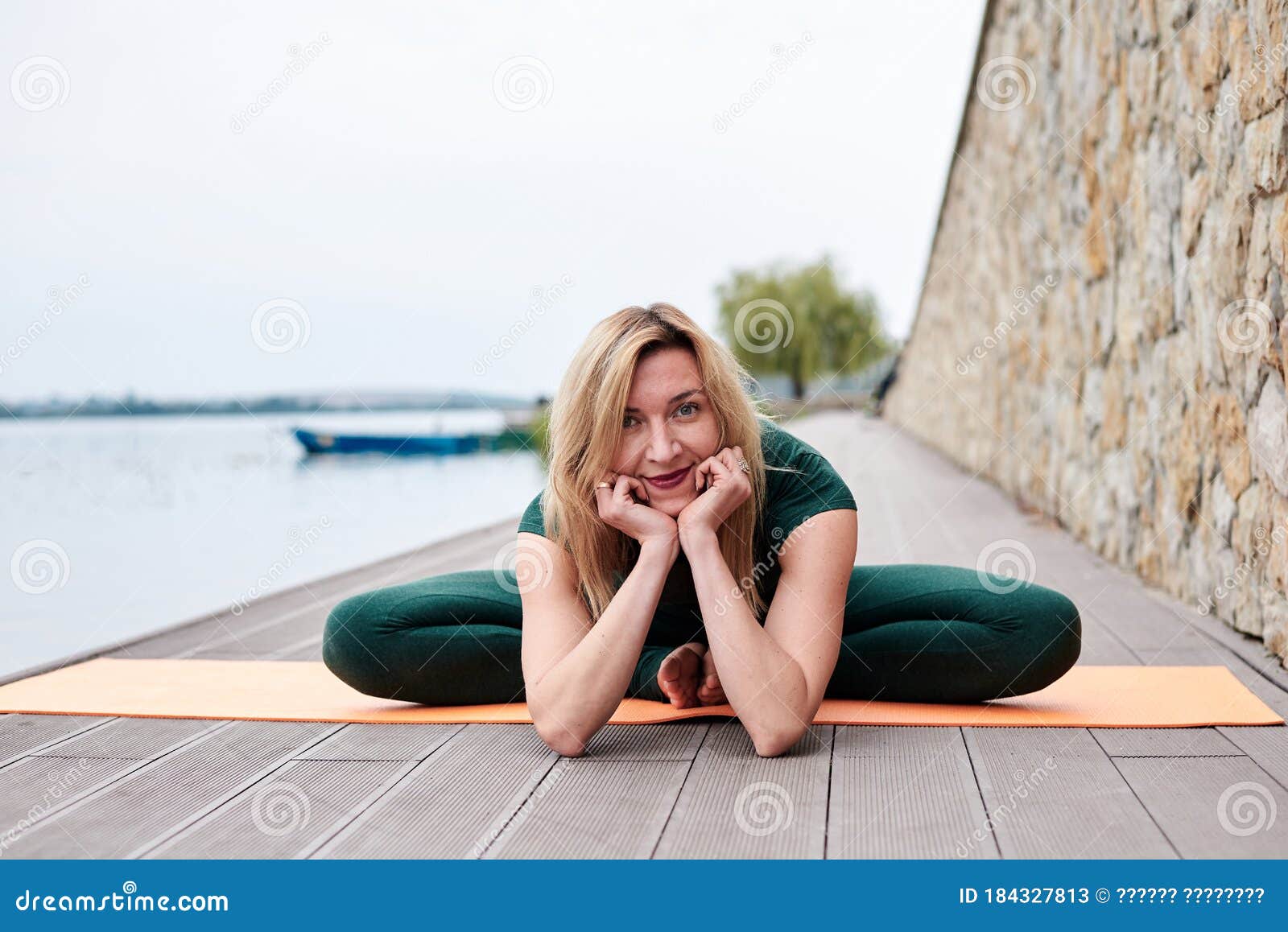 Young Blond Woman Wearing Green Overall With Bare Feet Doing Yoga Pose