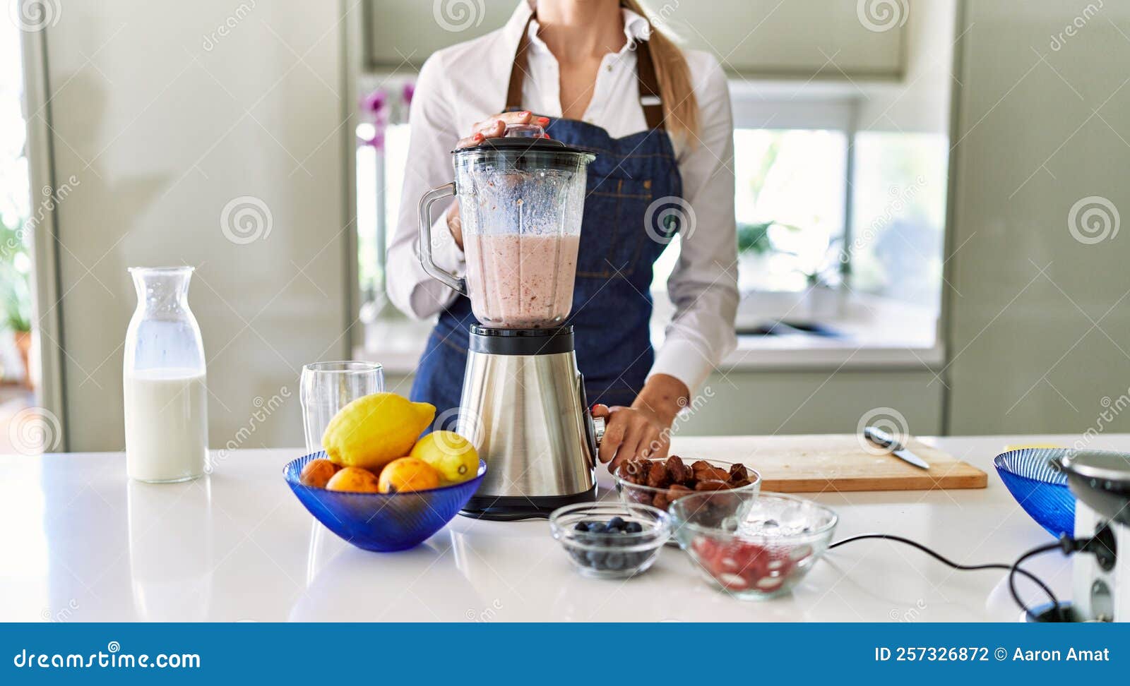 Young Blonde Woman Liquefying Smoothie Using Bender at Kitchen Stock ...