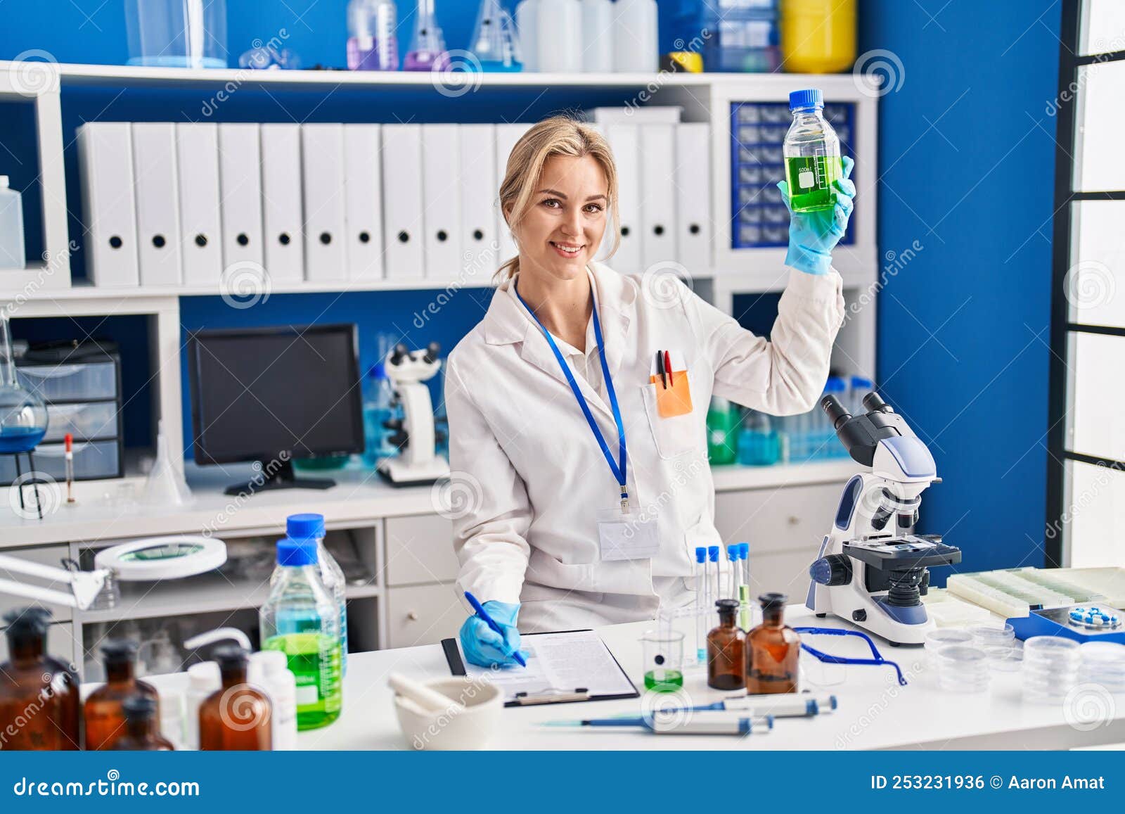 Young Blonde Woman Scientist Measuring Liquid Writing on Document at ...