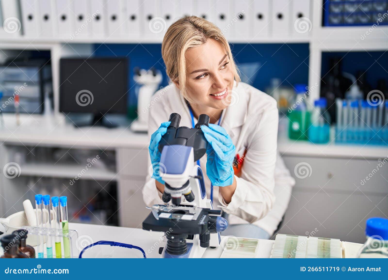 Young Blonde Woman Scientist Using Microscope Working at Laboratory ...