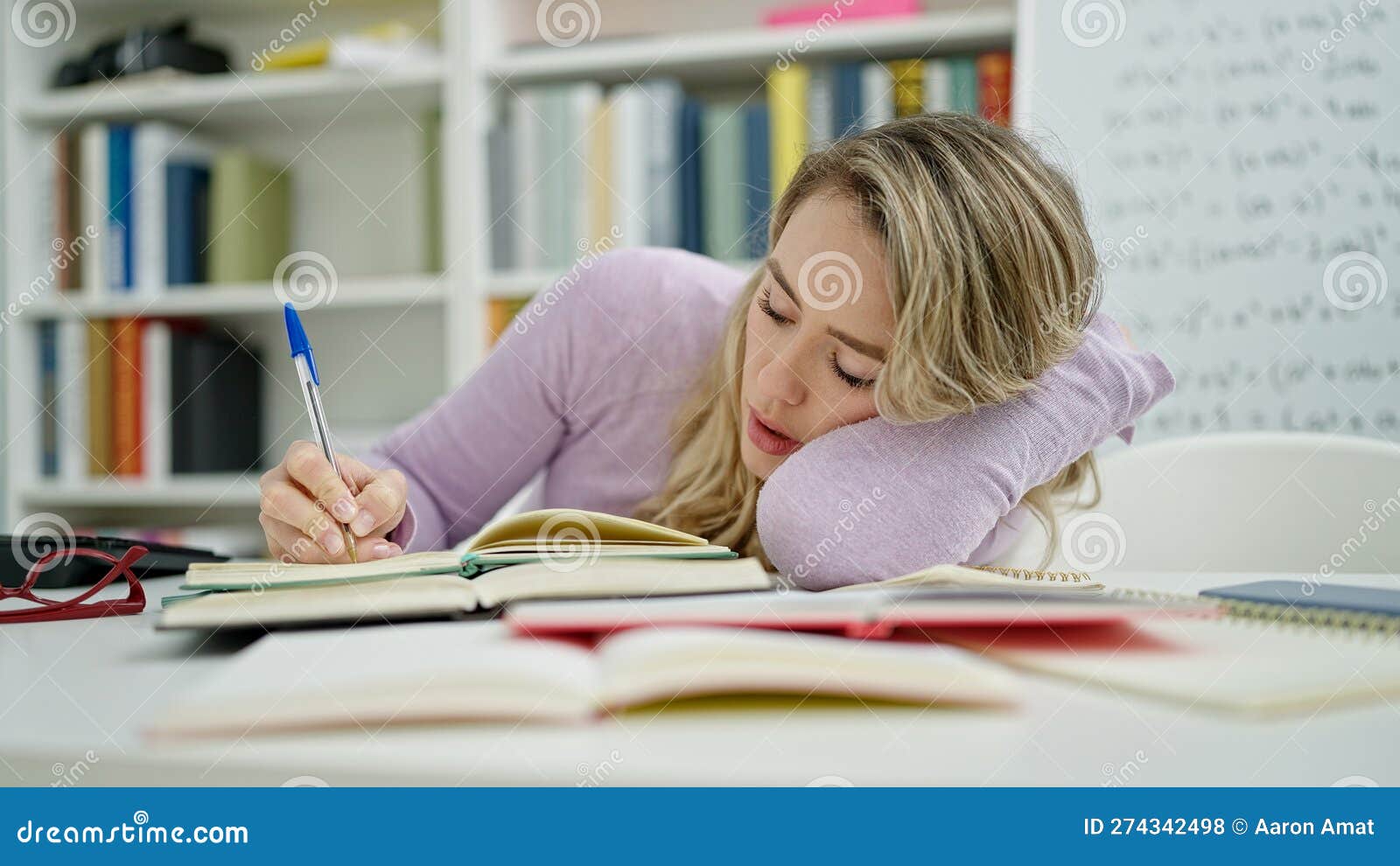 Young Blonde Woman Student Tired Writing Notes at Classroom Stock Photo ...