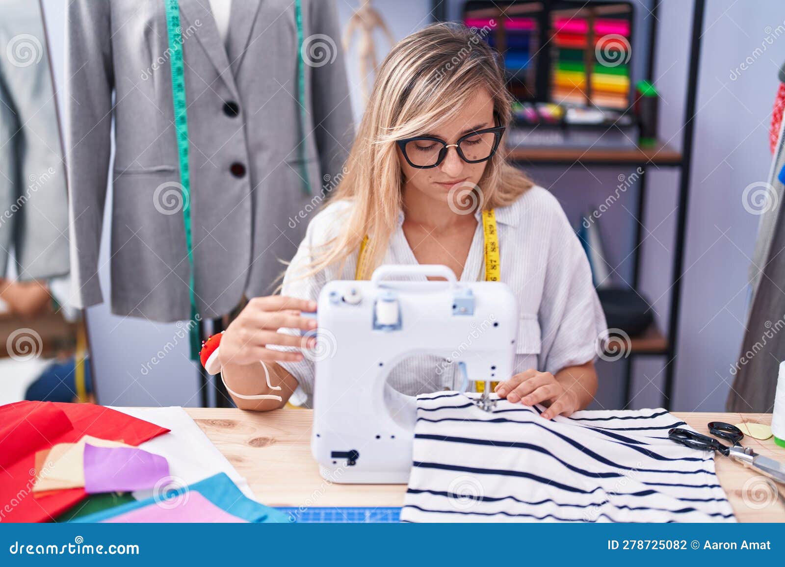 Young Blonde Woman Tailor Using Sewing Machine at Tailor Shop Stock ...