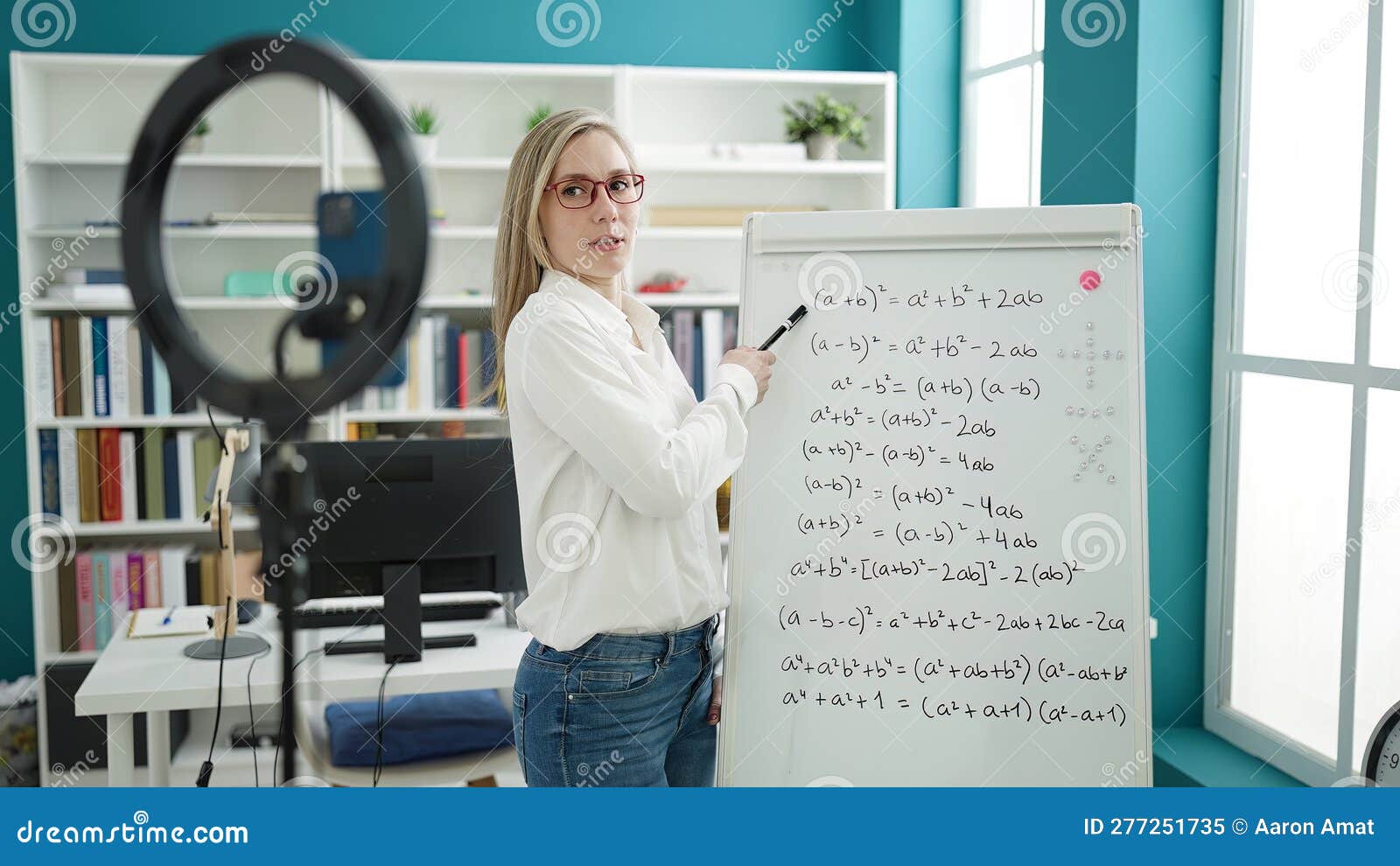 Young Blonde Woman Teacher Explaining Online Maths Exercise at Library ...