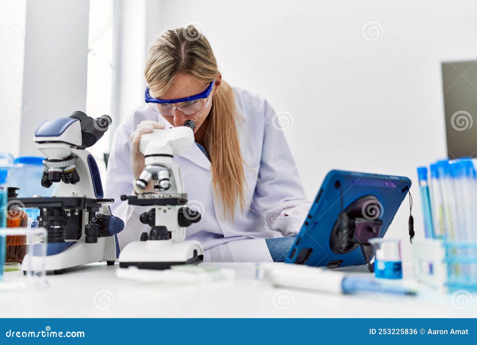 Young Blonde Woman Wearing Scientist Uniform Using Microscope and ...