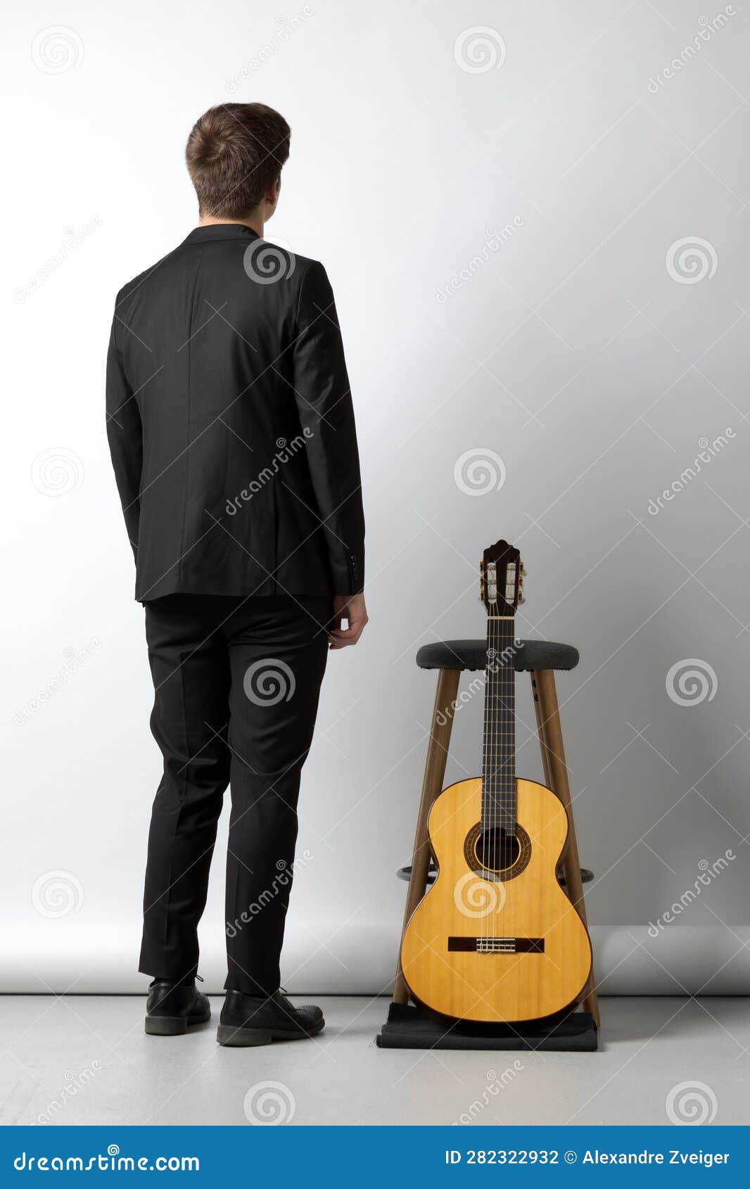 Young Boy from Behind in a Black Suit, Leaning on a Stool with His ...