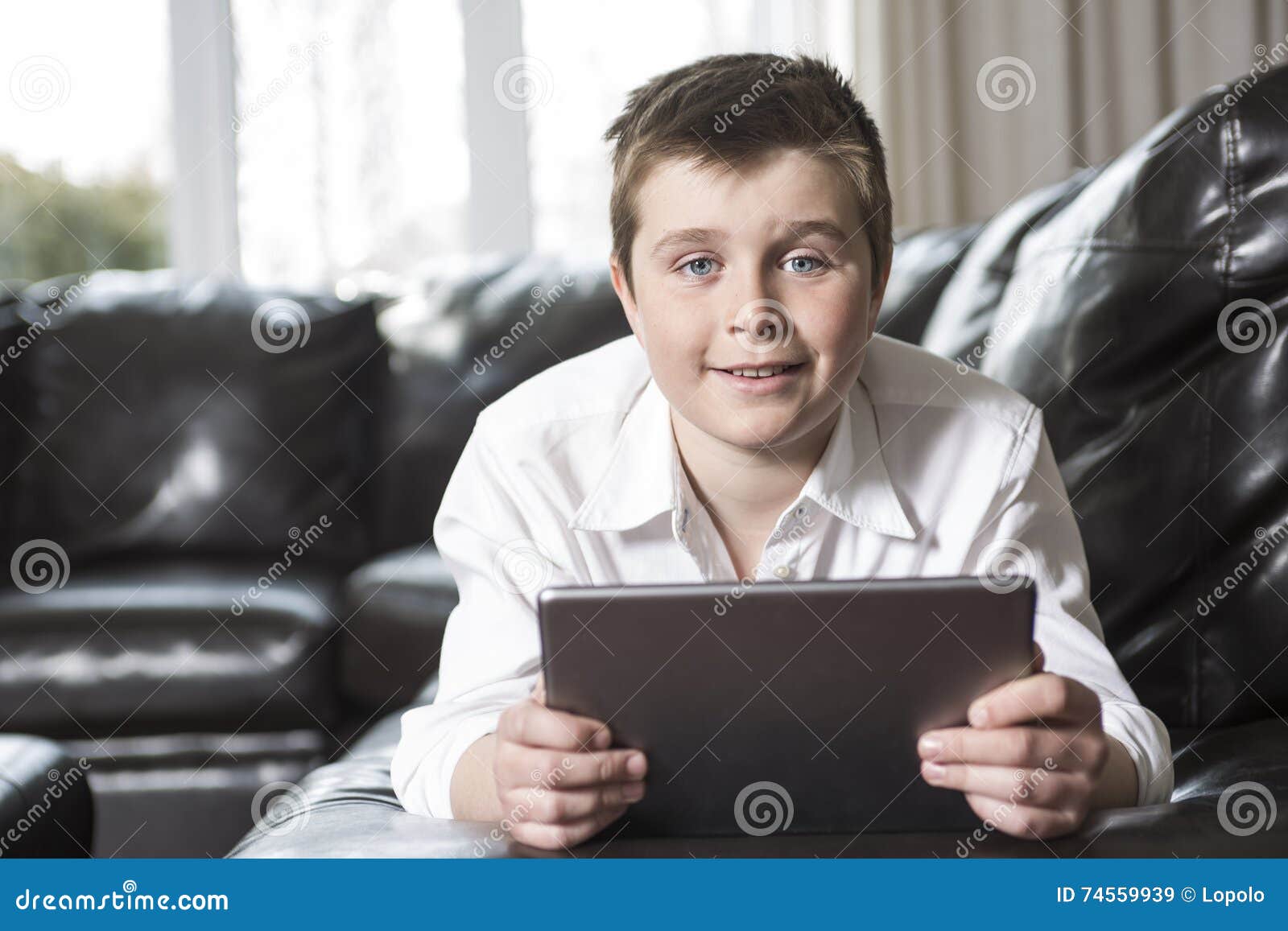 Young Boy Child Resting on His Hands Laying Down a Sofa Using Tablet ...