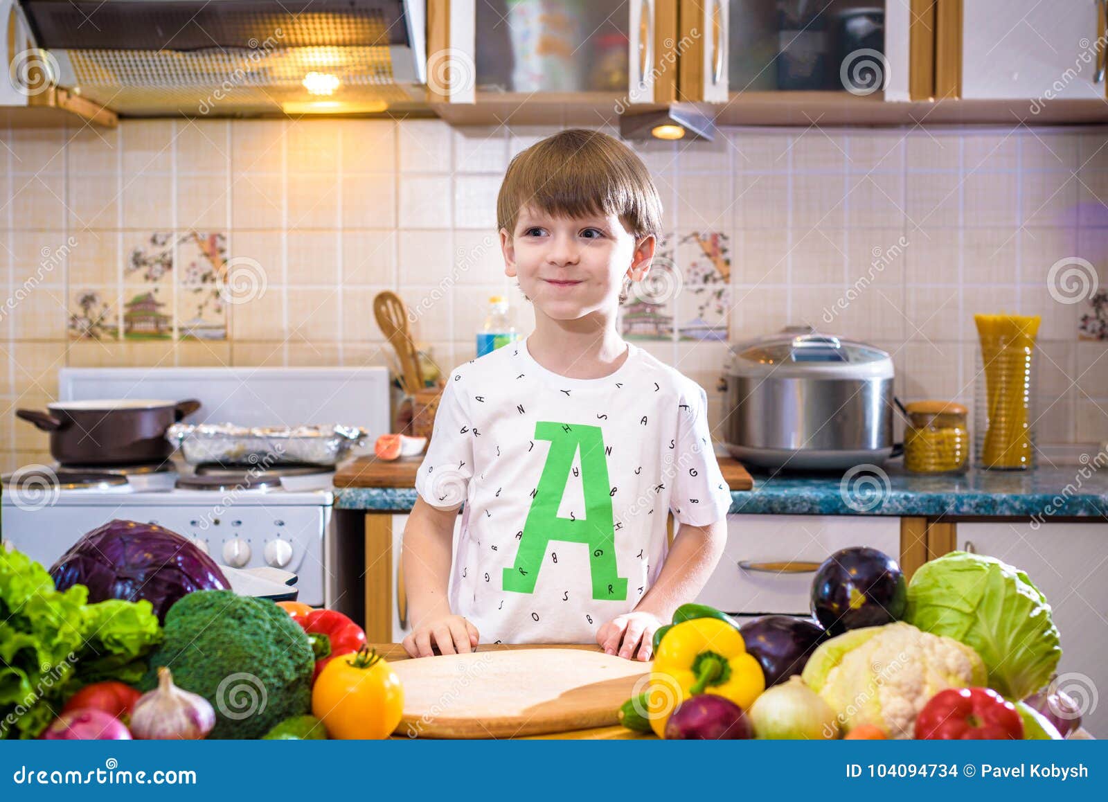The Young Boy in Cooking Standing in the Kitchen Near Table with Stock ...