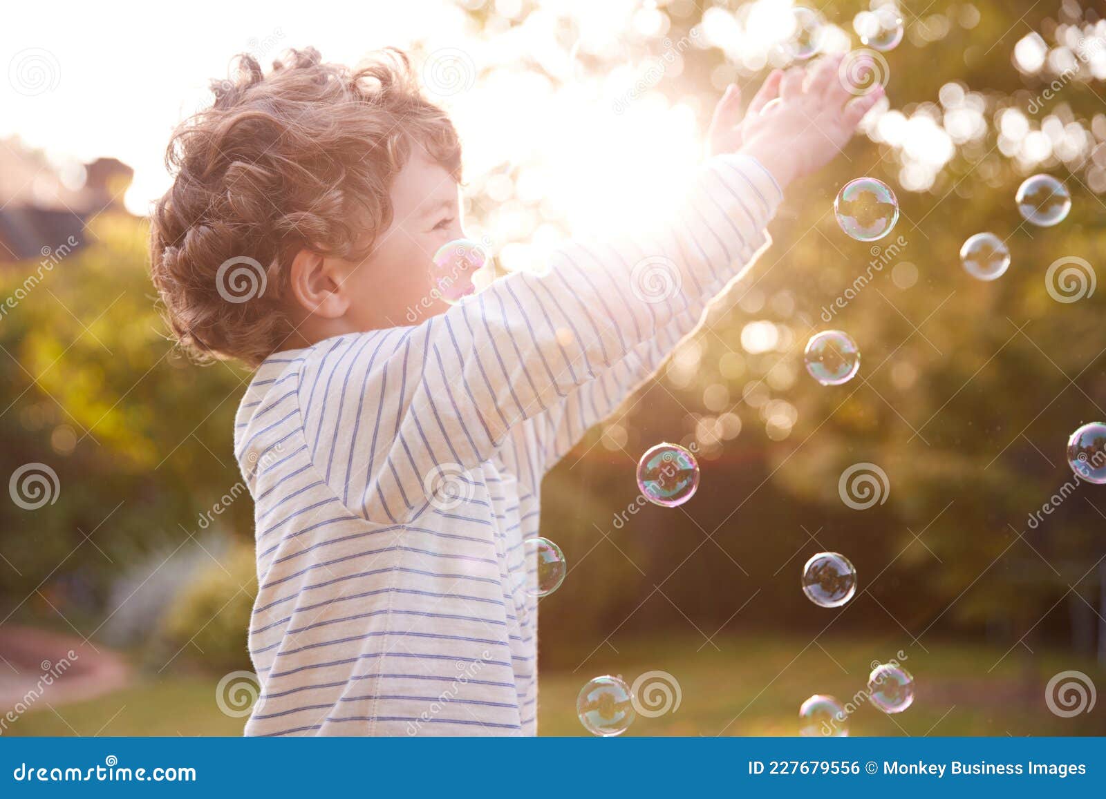 Young Boy Having Fun in Garden Chasing and Bursting Bubbles Stock Photo ...