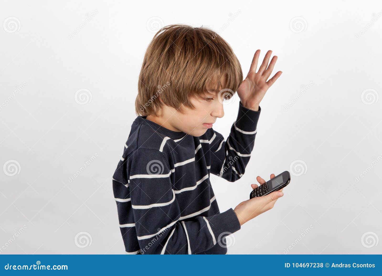 Young Boy Holding a Basic Mobile Phone and Not Too Happy with it Stock ...