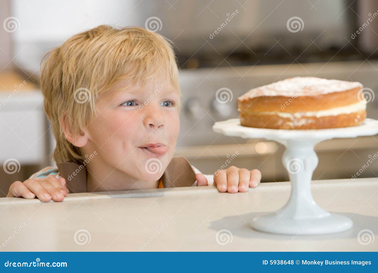 Young Boy in Kitchen Looking at Cake on Counter Stock Photo - Image of ...