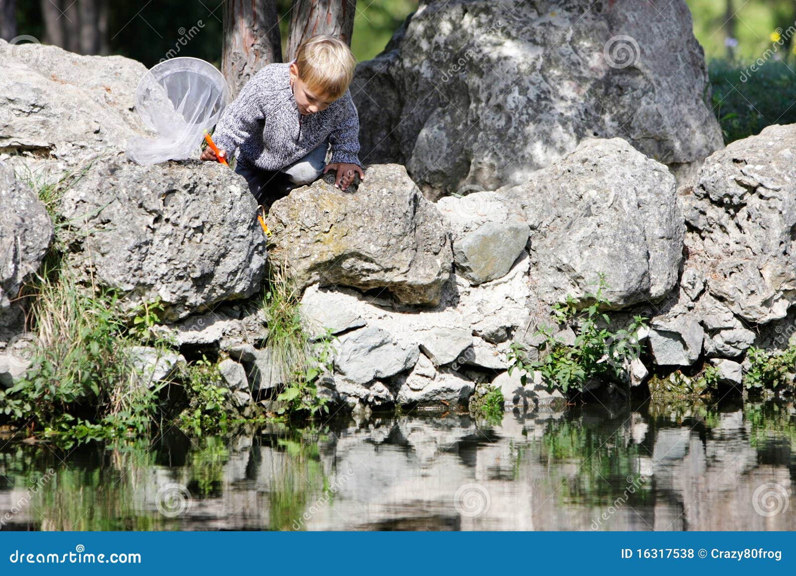 Young Boy on Rocks and Looking into Water Stock Photo - Image of ...