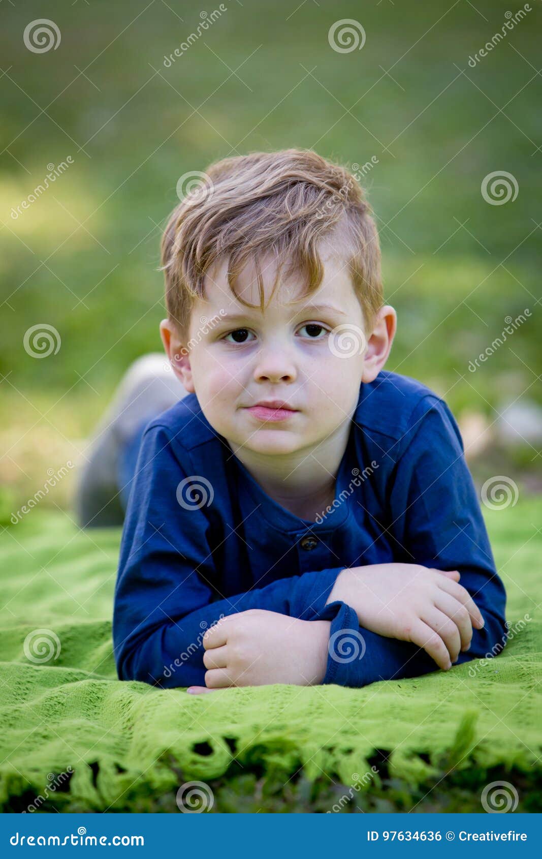 Young Boy with Serious Expression on Face Laying on Blanket Outdoors ...