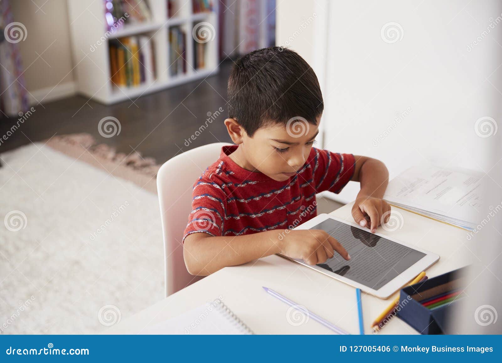 Young Boy Sitting at Desk in Bedroom Using Digital Tablet To Do ...