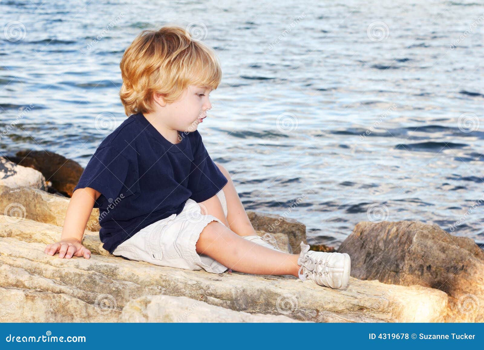 Young Boy Sitting by the Edge of a Lake Stock Photo - Image of rocks ...