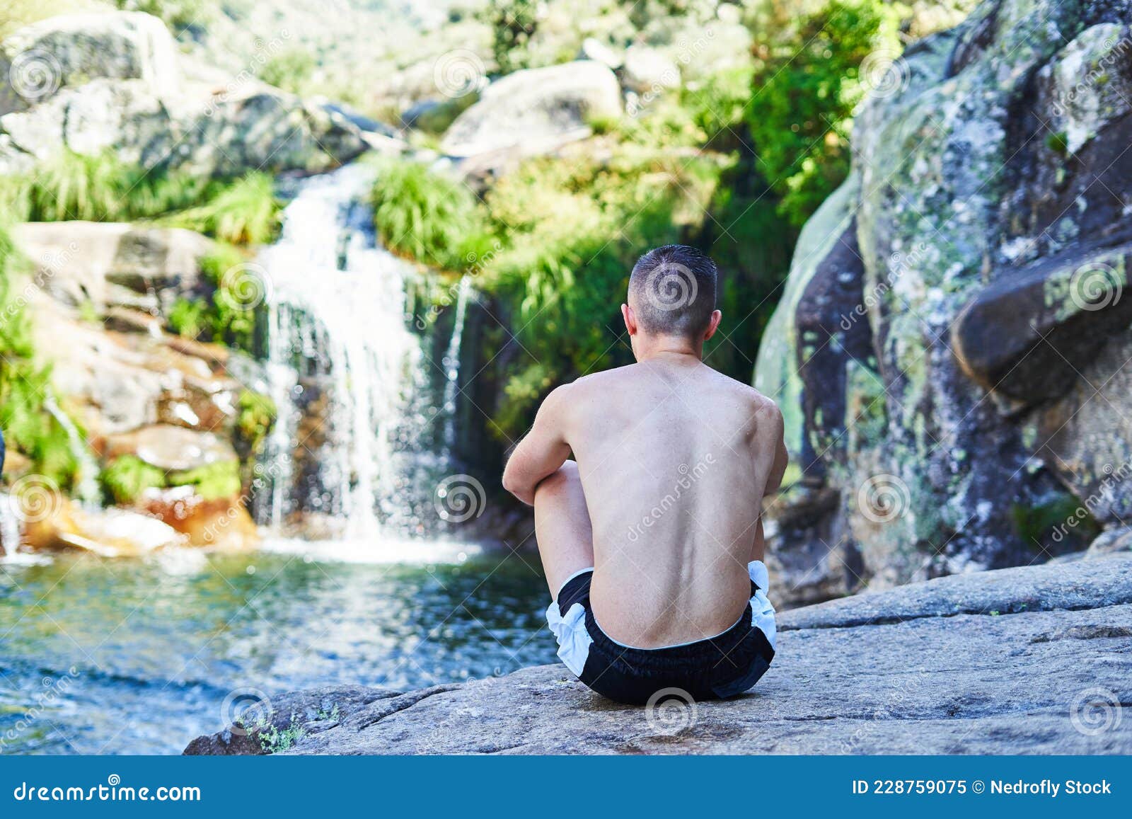 Young Boy Sitting on His Back on a Rock Looking at the River with ...