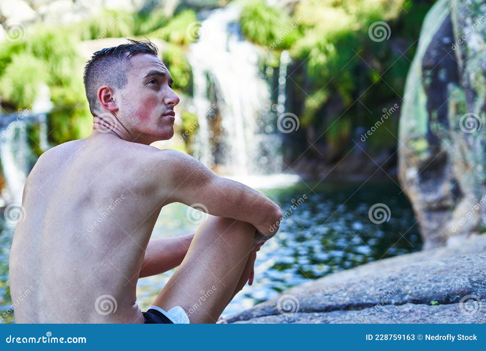 Young Boy Sitting on a Rock Looking at the River with Waterfall Stock ...