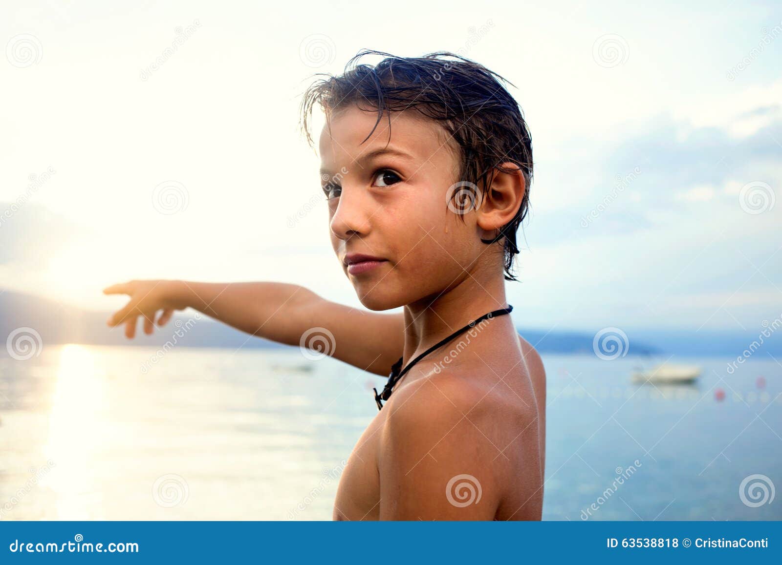 Young Boy Standing Pointing into the Sky in Front of Sea Stock Photo ...
