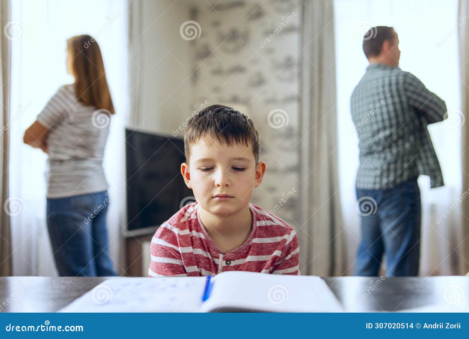 Young Boy Studying with Parents Arguing in Background Stock Photo ...