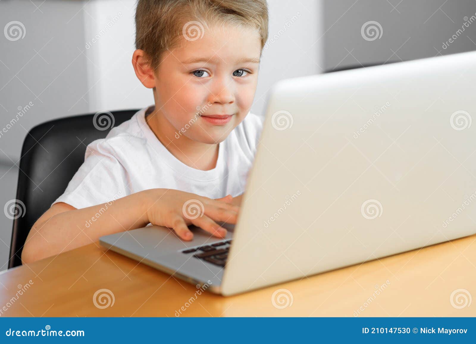 A Young Boy Using a Laptop Computer Sitting on Top of a Table at Home ...