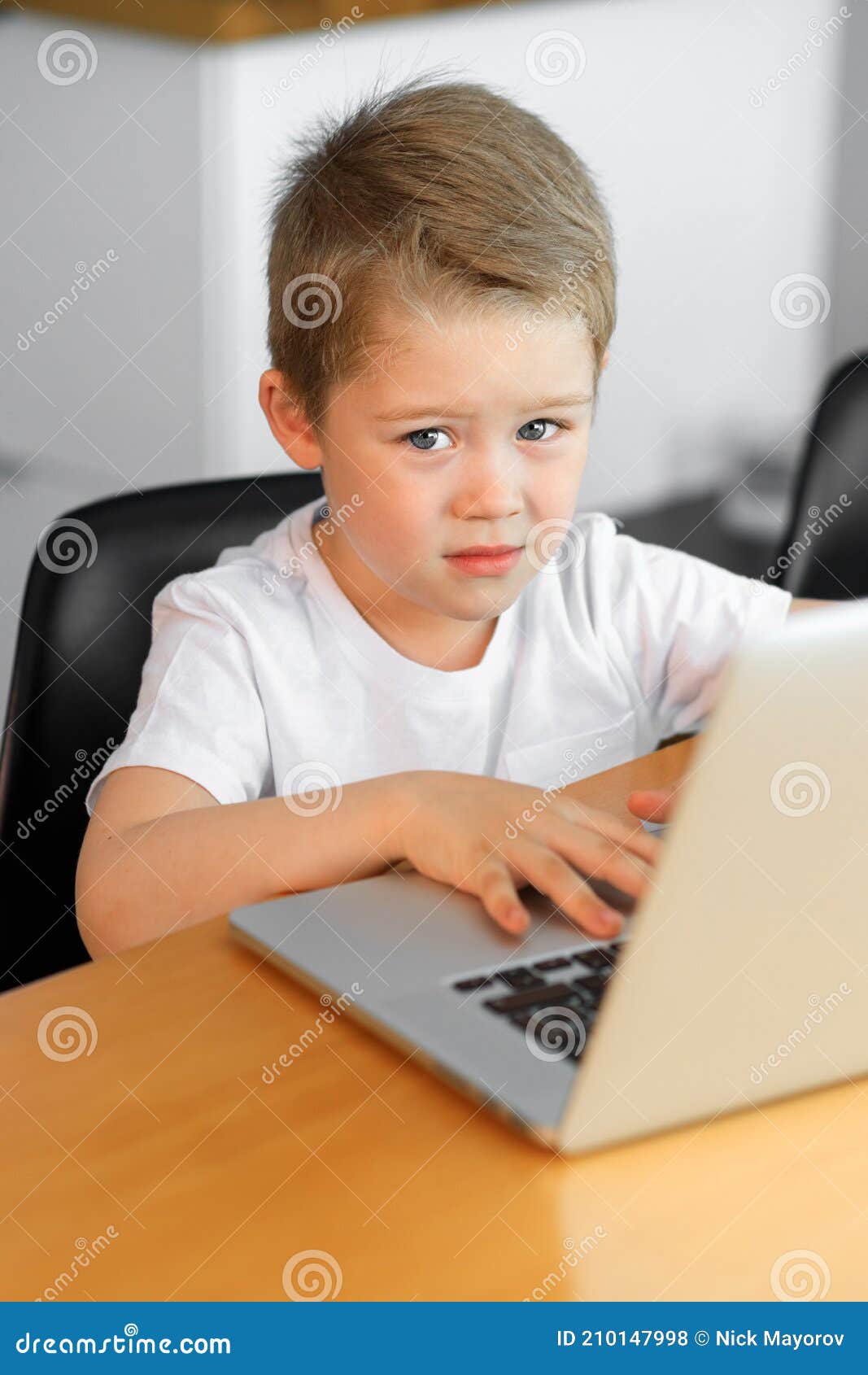 A Young Boy Using a Laptop Computer Sitting on Top of a Table at Home ...