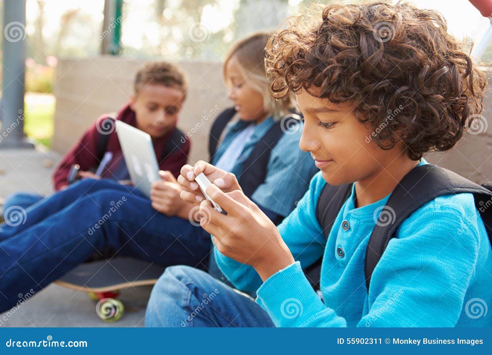 Young Boys Using Digital Tablets and Mobile Phones in Park Stock Image ...