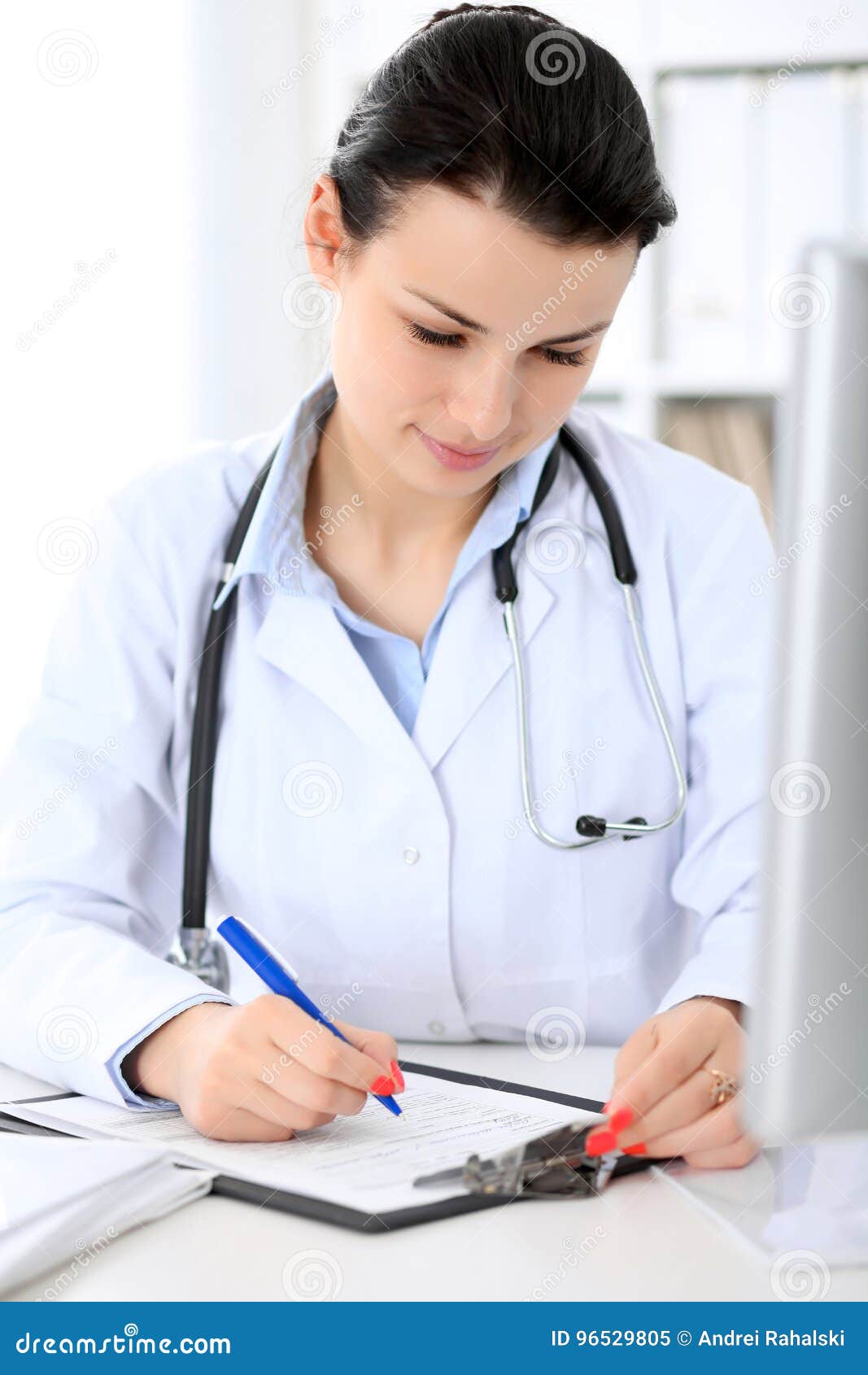 Young Brunette Female Doctor Sitting At The Table And Working At