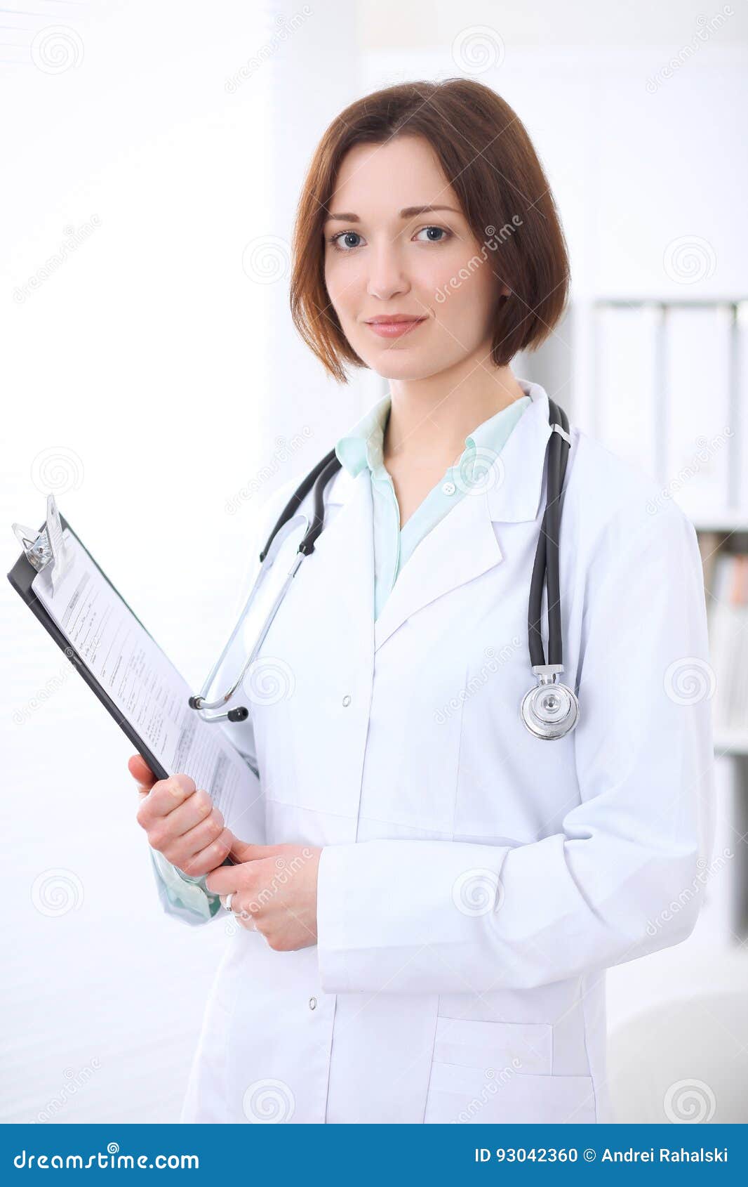 Young Brunette Female Doctor Standing With Arms Crossed And Smiling At