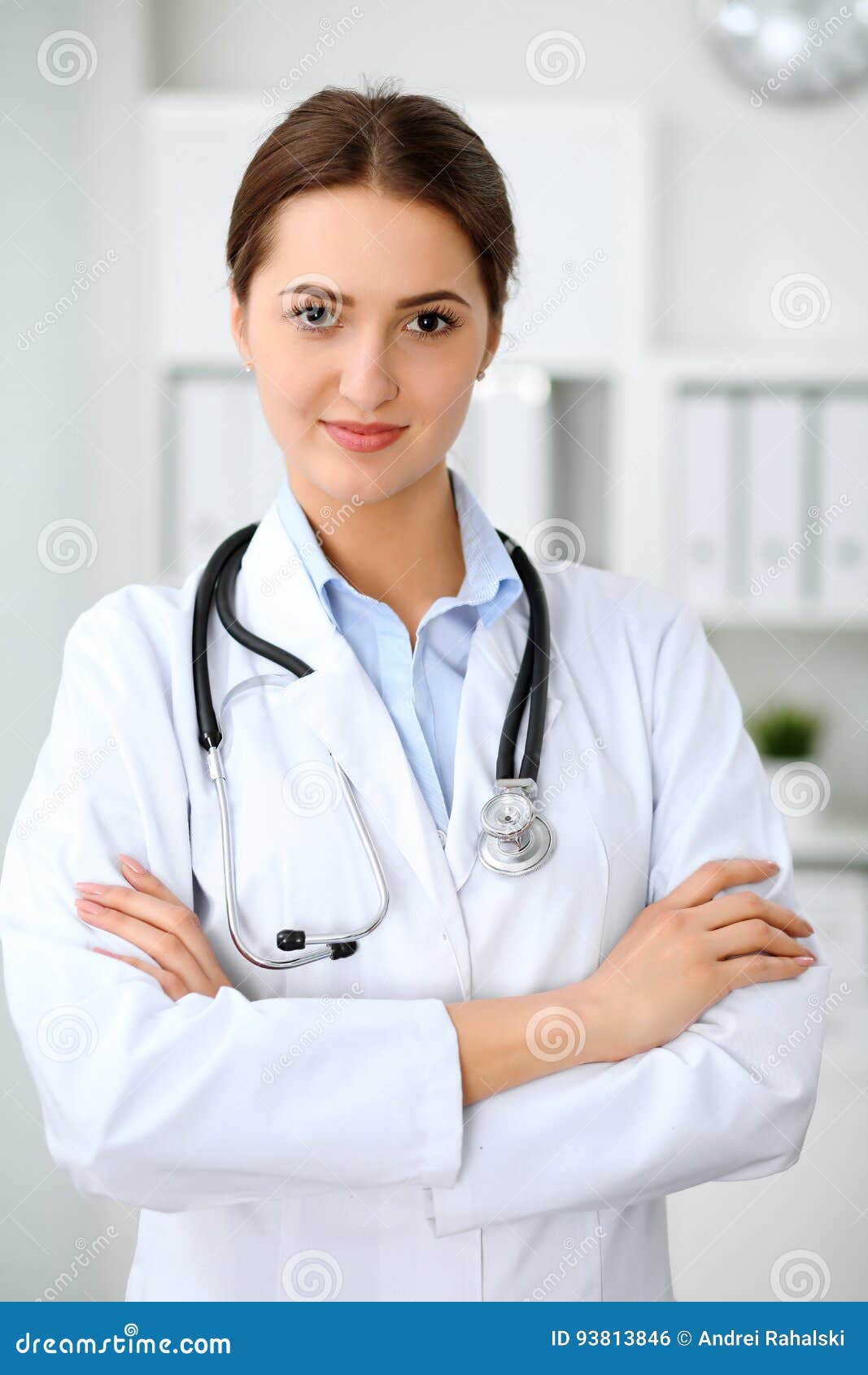 Young Brunette Female Doctor Standing With Arms Crossed And Smiling At