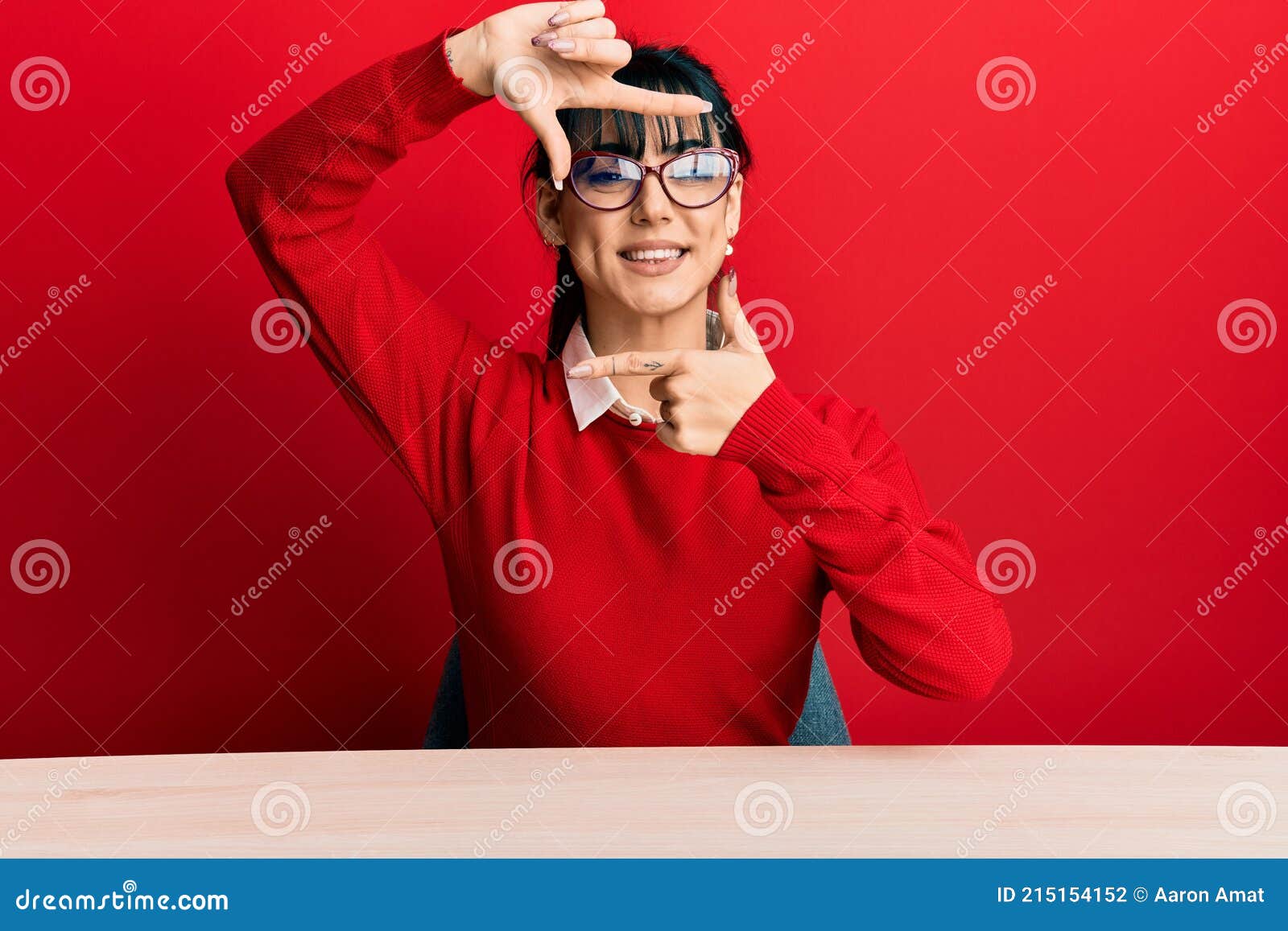 Young Brunette Woman With Bangs Wearing Glasses Sitting On The Table
