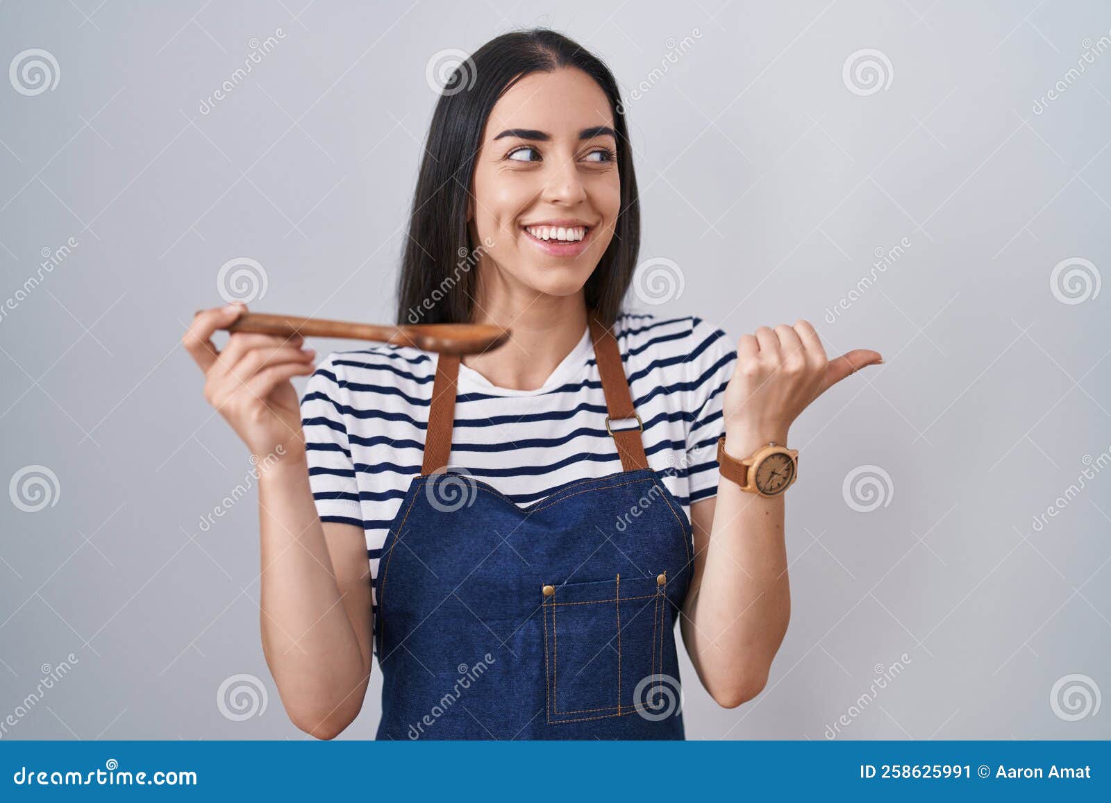 Young Brunette Woman Wearing Apron Tasting Food Holding Wooden Spoon ... Young Brunette Woman Wearing Apron Tasting Food Holding Wooden Spoon ...