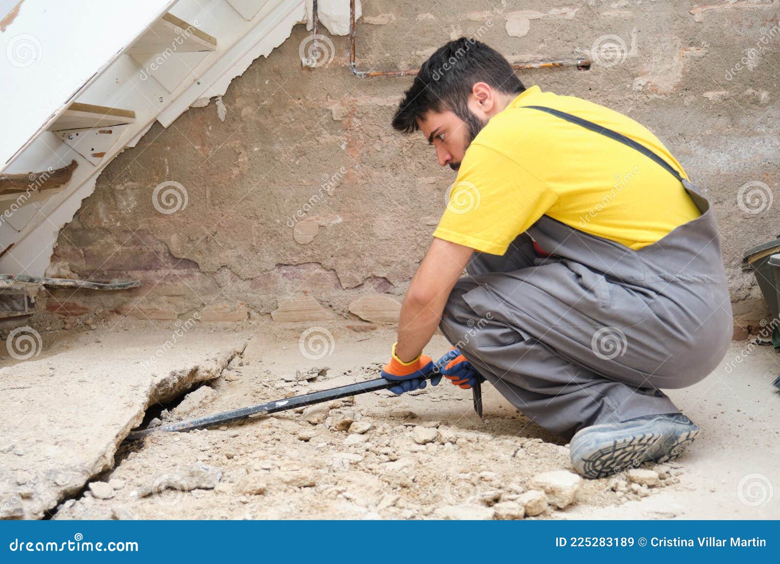 Young Builder Breaking Up a House Floor with a Crowbar. Stock Image ...