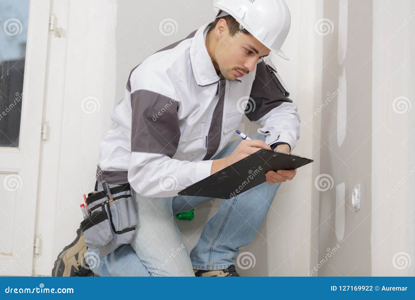 Young Builder Writing Something in Hardhat with Clipboard Stock Photo ...