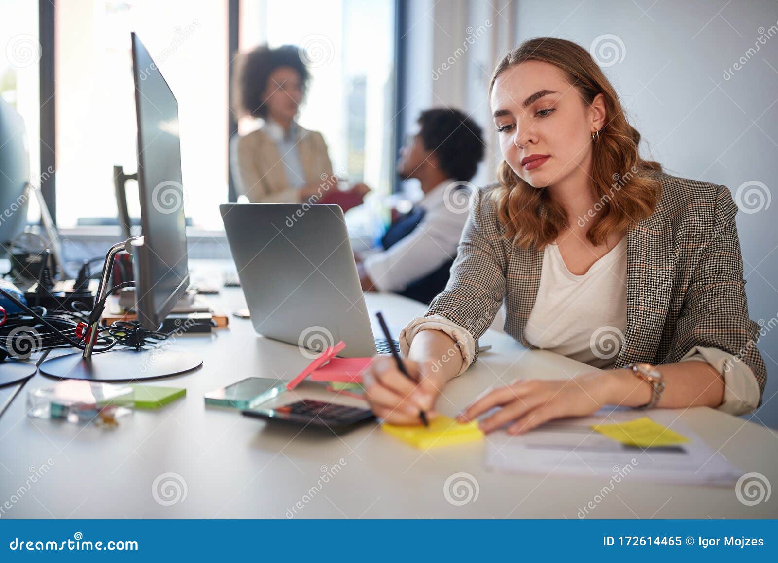 Young Business Woman Writing Down Reminder on a Sticky Note in Office ...