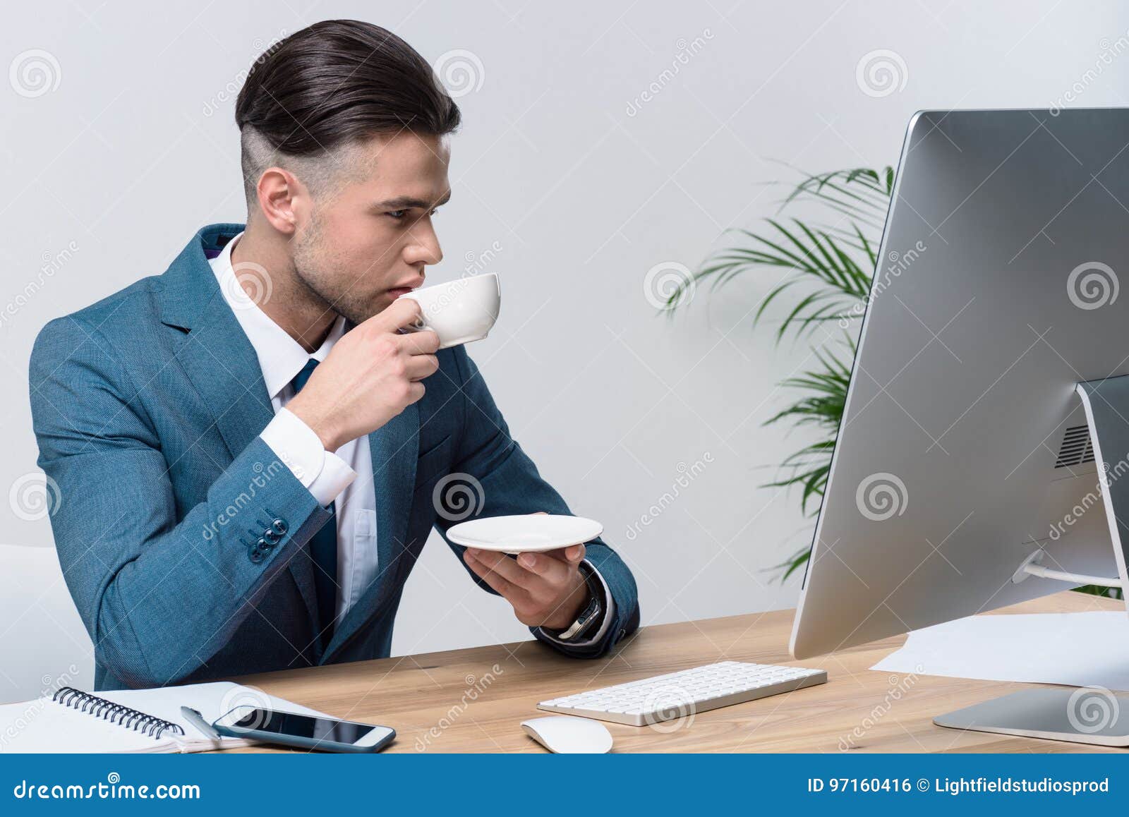 Young Businessman Drinking Coffee while Using Desktop Computer in ...