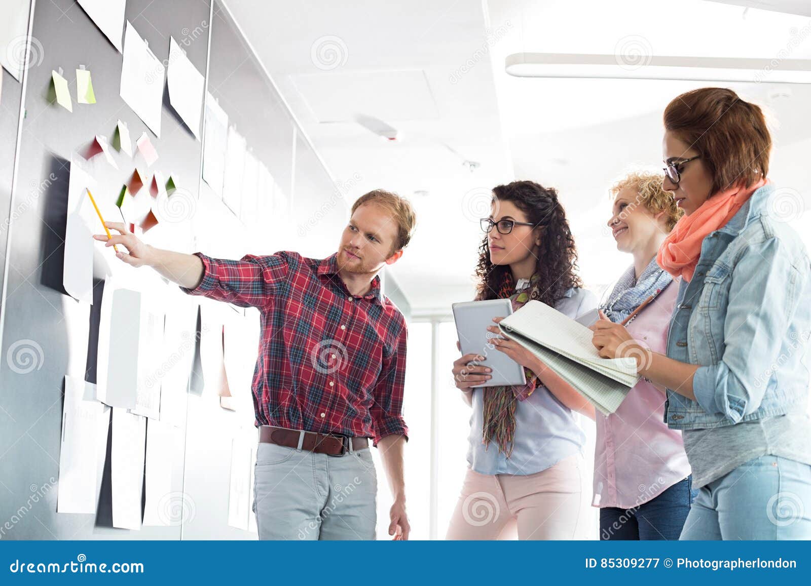 Young Businessman Explaining Document To Female Colleagues in Creative ...