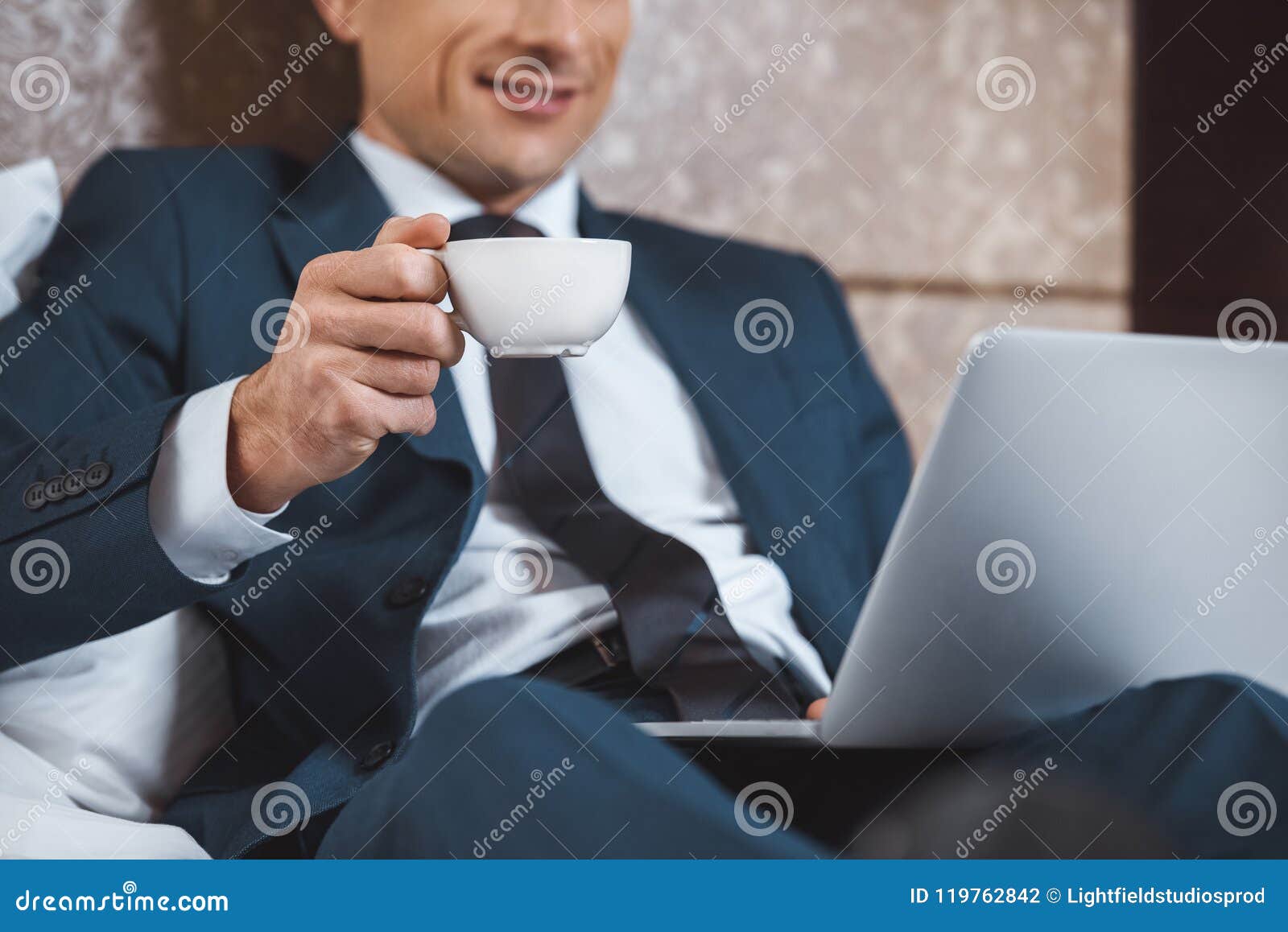 Young Businessman in Formal Suit Using His Laptop and Holding Cup of ... Young Businessman in Formal Suit Using His Laptop and Holding Cup of ...